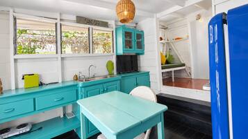 Uma cozinha com armários cor verde-água, pia e sala de jantar com mesa e cadeiras.