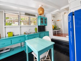 Uma cozinha com armários cor verde-água, pia e sala de jantar com mesa e cadeiras.