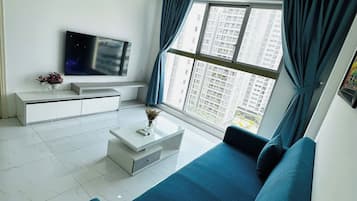 Uma sala de estar moderna com uma televisão de tela plana grande, um sofá azul e uma mesa de centro.