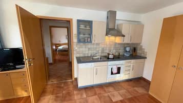 Uma cozinha compacta com forno embutido, micro-ondas e pia.