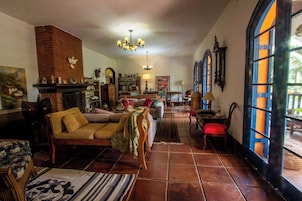 Uma sala de estar aconchegante com lareira, um sofá, um espaço de refeições e uma janela ampla com vista.