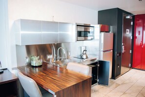 Cozinha moderna com eletrodomésticos de aço inoxidável, mesa de jantar de madeira e um armário vermelho.