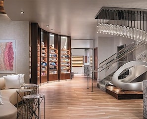 Um interior moderno com piso de madeira, um sofá, área de jantar, escada de design exclusivo e uma grande coleção de objetos nas prateleiras.