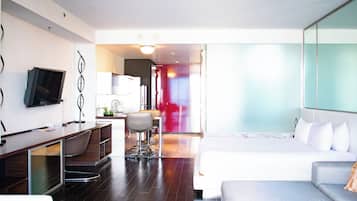 Quarto de hotel moderno com cama, escrivaninha, cadeira e televisão.