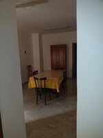 Uma sala de jantar com uma mesa coberta por uma toalha amarela, rodeada por cadeiras.