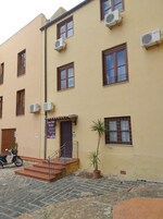 Um edifício de vários andares com aparelhos de ar condicionado, uma pequena entrada com degraus e uma planta em vaso.