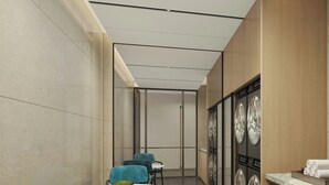 Quarto de hotel moderno com área de estar, incluindo duas cadeiras, uma mesa, máquina de lavar embutida e chão em piso de mármore.