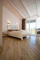 Quarto com cama, mesa de cabeceira e vista para o exterior.