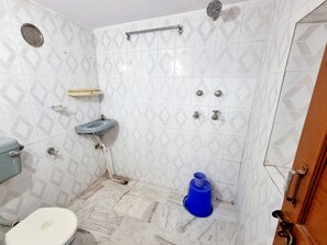 Casa de banho com sanita, lavatório, chuveiro e um balde azul.