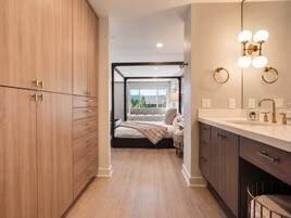 Quarto moderno com uma cama grande, mesa de cabeceira e vista para o exterior.
