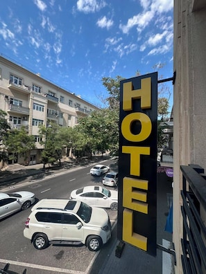 Placa de hotel com vista clara para a rua e carros estacionados.
