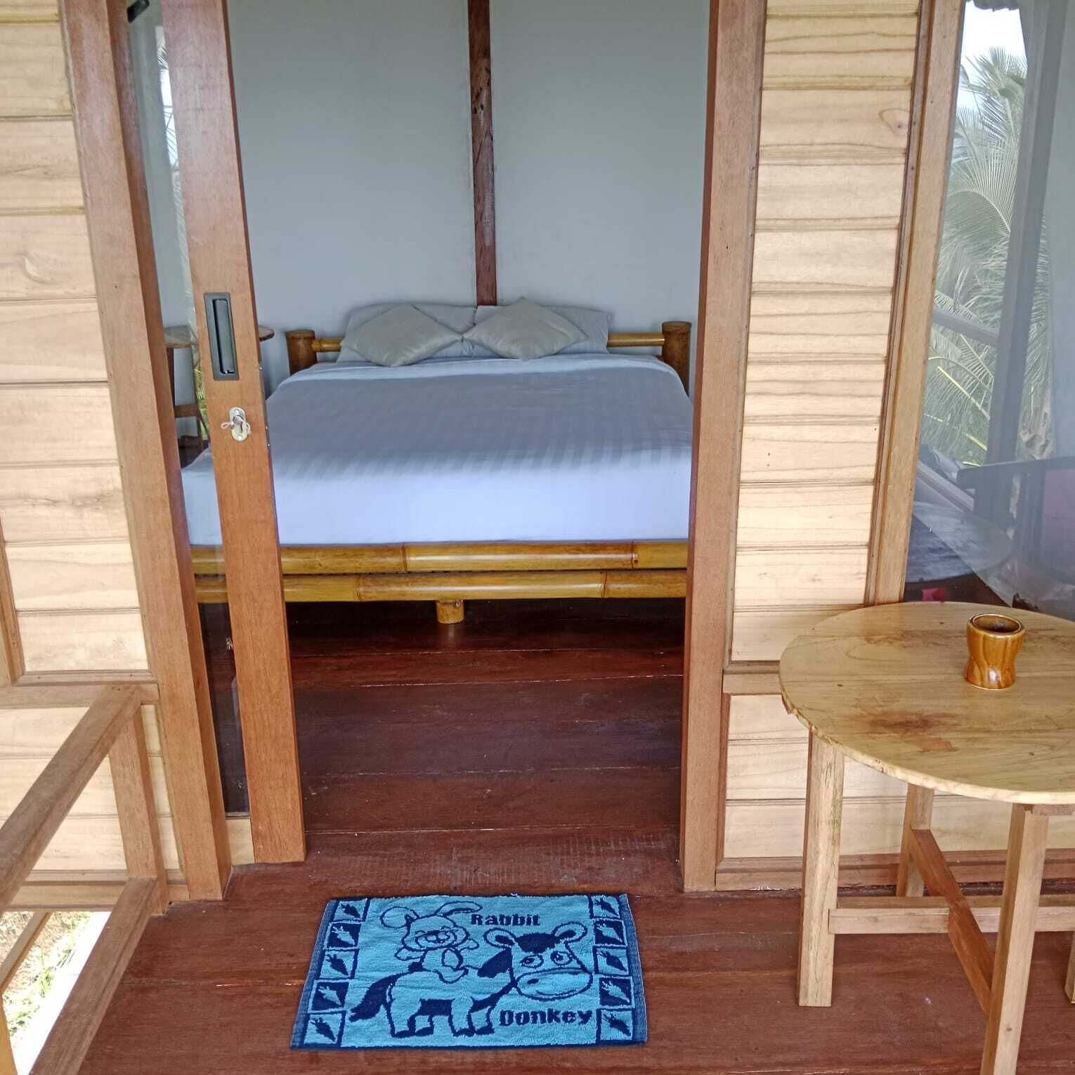 Quarto de madeira com uma cama, uma mesinha e um tapete com desenhos de animais.