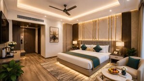 Quarto de hotel moderno com uma cama grande, área de estar, televisão de tela plana e ventilador de teto.