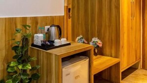 Um quarto de madeira com um armário de madeira, uma pequena mesa com uma chaleira, xícaras e garrafas, e uma planta.