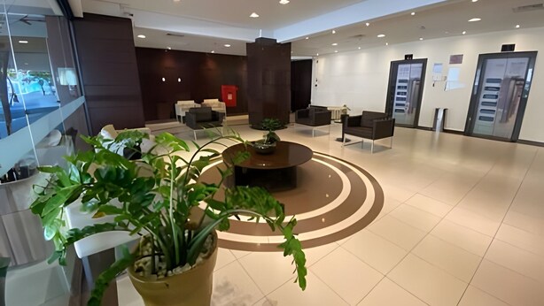 Um lobby moderno com área de estar central, balcão de recepção e uma grande janela.
