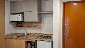 Uma cozinha compacta equipada com micro-ondas, cafeteira e um frigorífico pequeno.