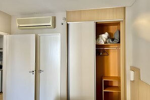 Quarto com guarda-roupa, espaço para pendurar roupas e ar condicionado.