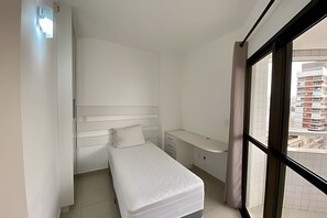Um quarto pequeno e moderno, com uma cama, uma escrivaninha e uma janela.