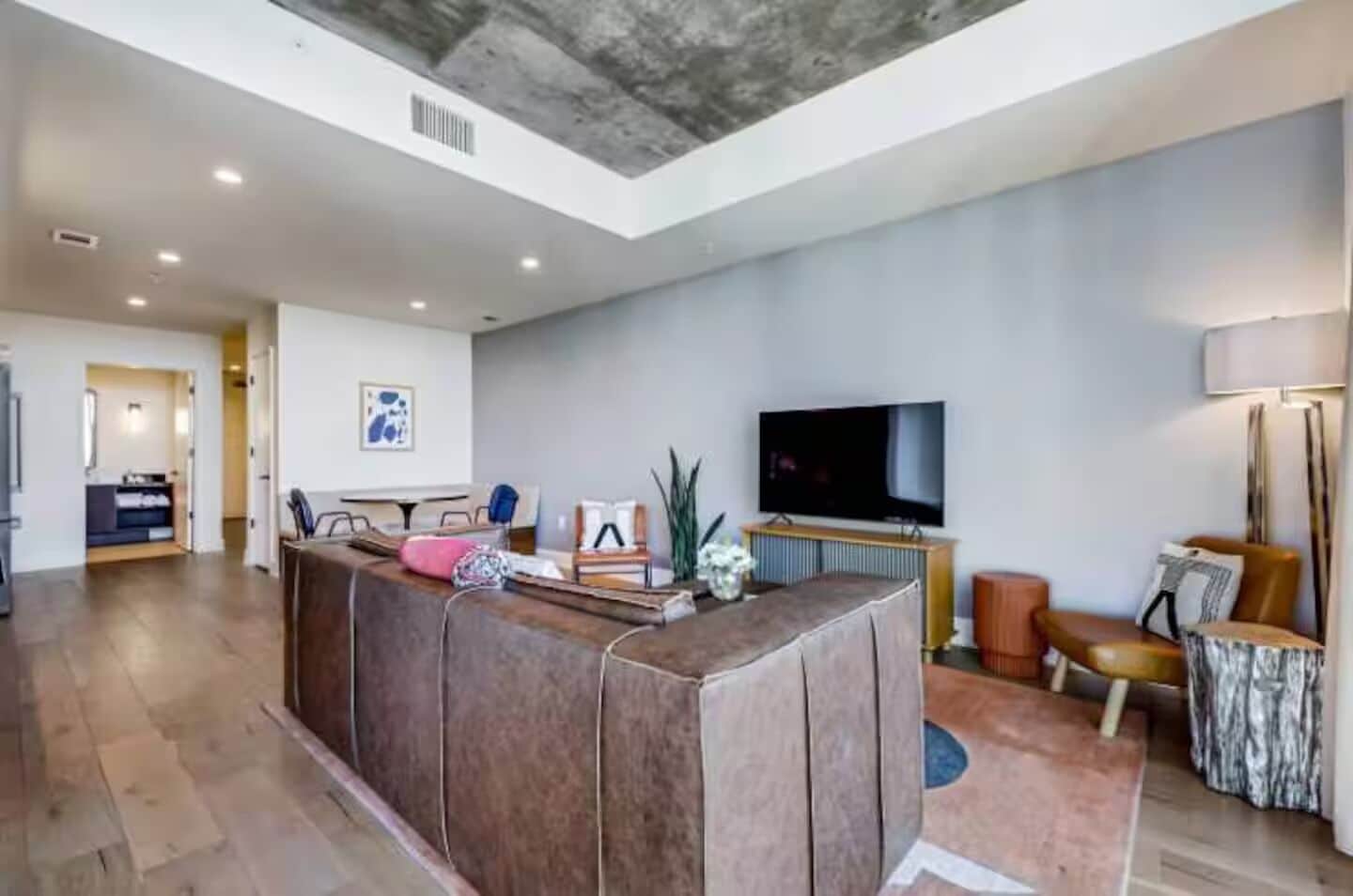 Uma sala de estar moderna com um grande painel de entretenimento, uma televisão de tela plana e um espaço de estar com sofá e poltronas.