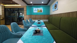 Uma sala de conferências com uma mesa comprida, cadeiras e um sofá verde.