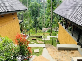 Um pátio com caminho de pedra, um pequeno jardim e dois edifícios com telhados de cerâmica.