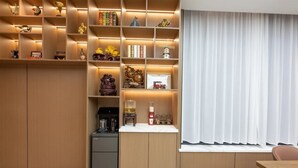 Cozinha moderna com prateleiras embutidas, máquina de café e janela com cortinas.
