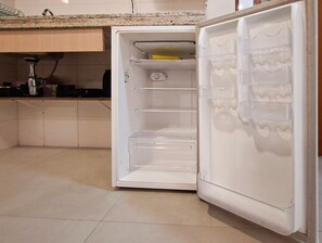 Geladeira aberta com prateleiras, compartimento para congelador e dispensador de água.