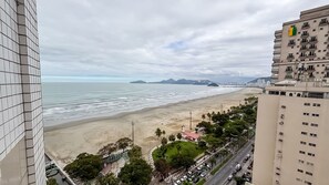 Um edifício alto com vista para uma praia e montanhas ao longe.