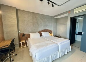 Quarto de hotel moderno com uma cama grande, uma mesa e uma cadeira.