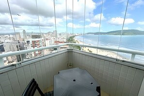 Varanda com vista para a praia e horizonte urbano.