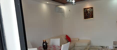 Uma sala de estar com mesa de jantar, sofá, piso de mármore e ventilador de teto.