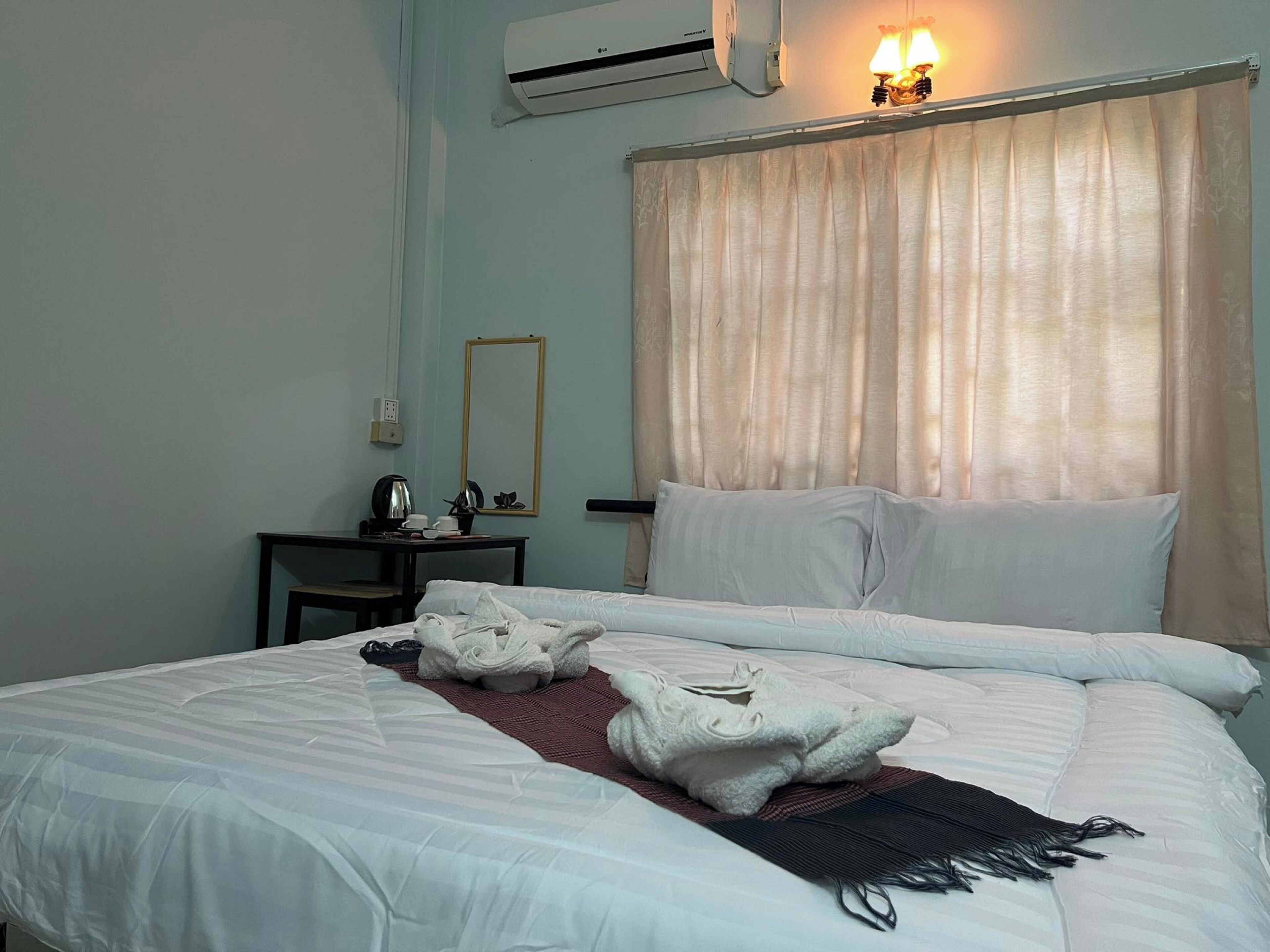 Quarto de hotel com cama, secretária, espelho e unidade de ar condicionado.