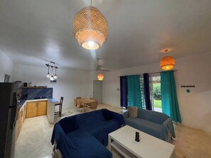 Uma sala de estar moderna com sofá, mesa de centro e área de jantar com mesa e cadeiras.