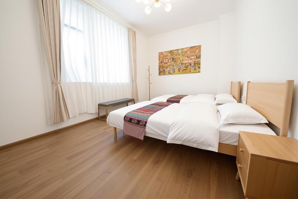 Um quarto com uma cama grande, uma mesa de cabeceira, um banco e um quadro na parede.