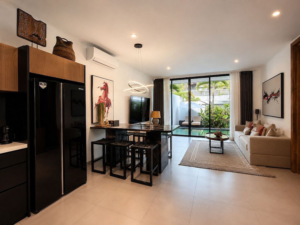 Uma sala de estar moderna com área de jantar, cozinha equipada com geladeira e uma grande janela com vista para o exterior.