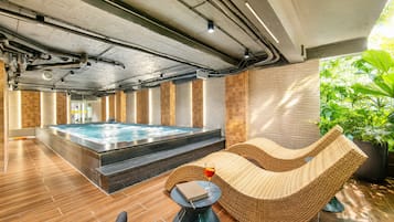 Uma área de spa com hidromassagem, piso de madeira e uma poltrona de vime.