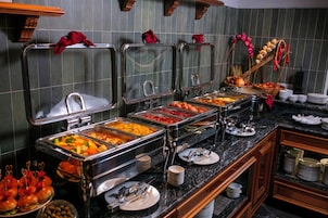 Disposição de buffet com várias estações de comida, incluindo uma variedade de pratos e uma seleção de frutas e legumes.