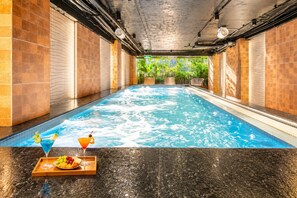 Piscina interna com vista para o verde exterior, rodeada por paredes revestidas com azulejos.