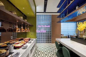Interior de restaurante moderno com buffet, letreiro neon e piso estampado.