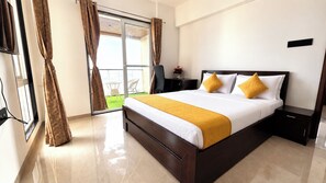 Quarto de hotel moderno com uma cama grande, uma mesa de cabeceira, uma escrivaninha e vista para o exterior.