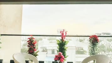 Uma varanda com cadeiras de vime, uma mesa redonda e plantas em vasos.