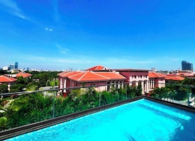 Piscina no terraço com vista desobstruída para prédios com telhados vermelhos e palmeiras.