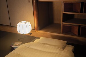 Uma cama com travesseiro branco e abajur sobre a mesa de cabeceira.