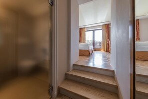 Escada que leva a uma varanda com vista, piso de madeira e teto branco.