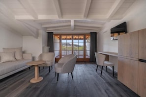 Um interior moderno com um sofá, cadeiras, uma mesa pequena e uma TV fixada na parede.