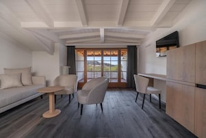 Um interior moderno com um sofá, cadeiras, uma mesa pequena e uma TV fixada na parede.