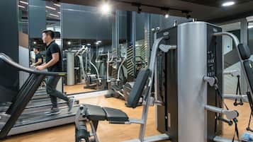 Uma academia com esteiras, aparelhos de musculação e um espelho grande.