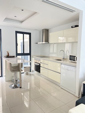 Uma cozinha moderna com uma ilha central, eletrodomésticos de aço inoxidável e uma máquina de lavar louça.