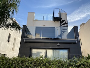 Um edifício moderno com fachada preta, varanda de vidro e escadaria em espiral.