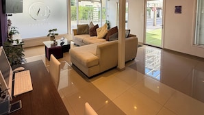 Um lobby de hotel moderno com um sofá, uma mesa com um computador e uma janela grande.